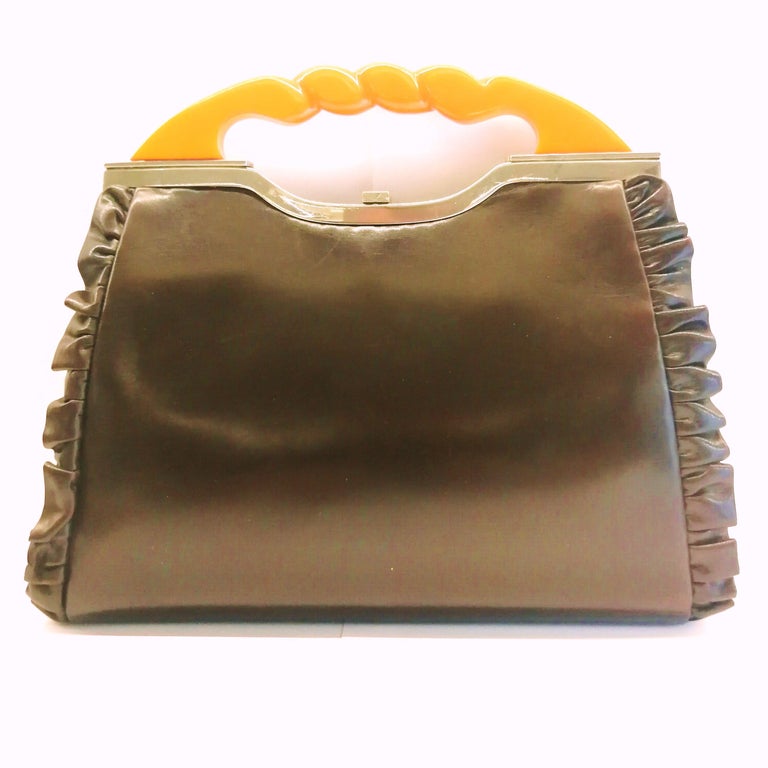 A brown leather handbag, with a carved amber Bakelite handle, English ...