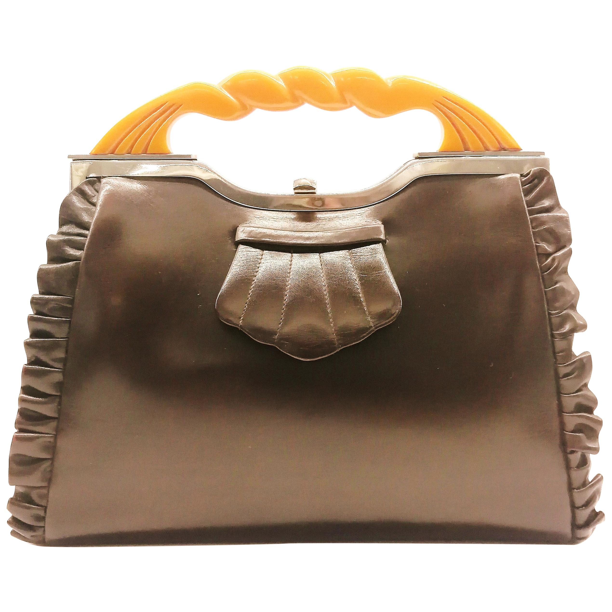 A brown leather handbag, with a carved amber Bakelite handle, English ...
