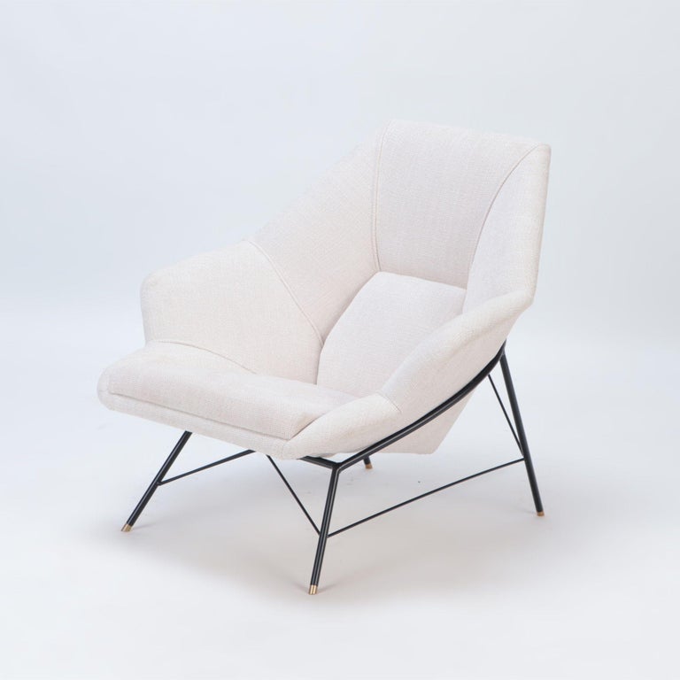 A pair of black iron frame club chairs with white upholstered seats ...