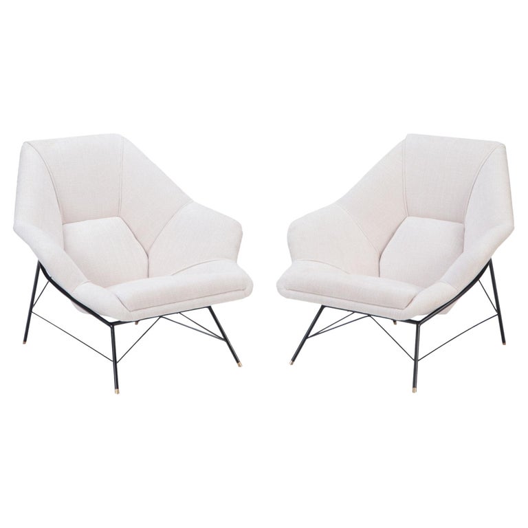A pair of black iron frame club chairs with white upholstered seats ...