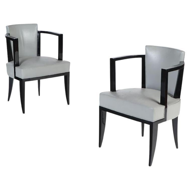 A Pair of French ebonized open arm chairs with faux leather upholstery ...
