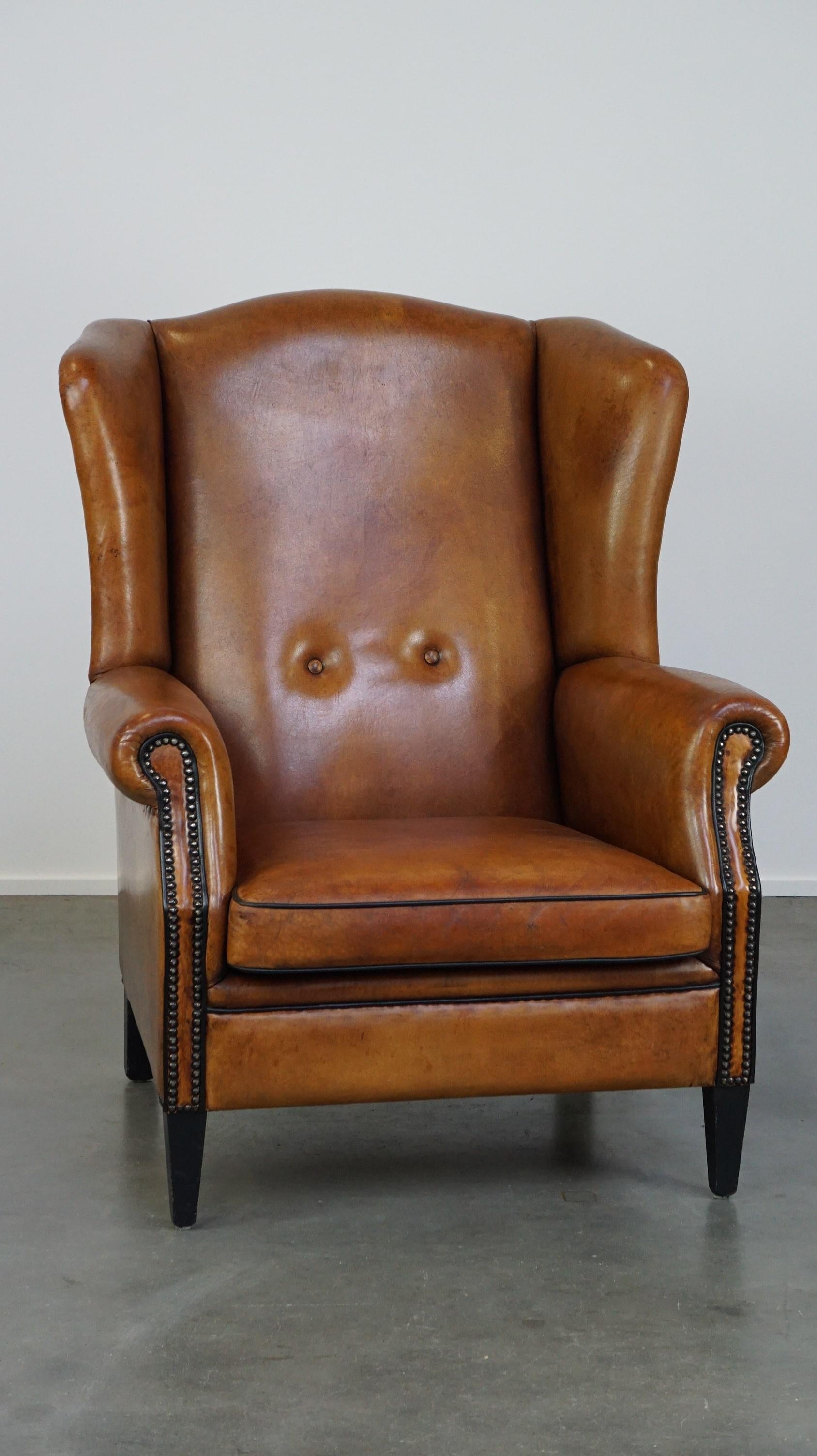 sheepskin wingchair with decorative nails, black piping and high ...