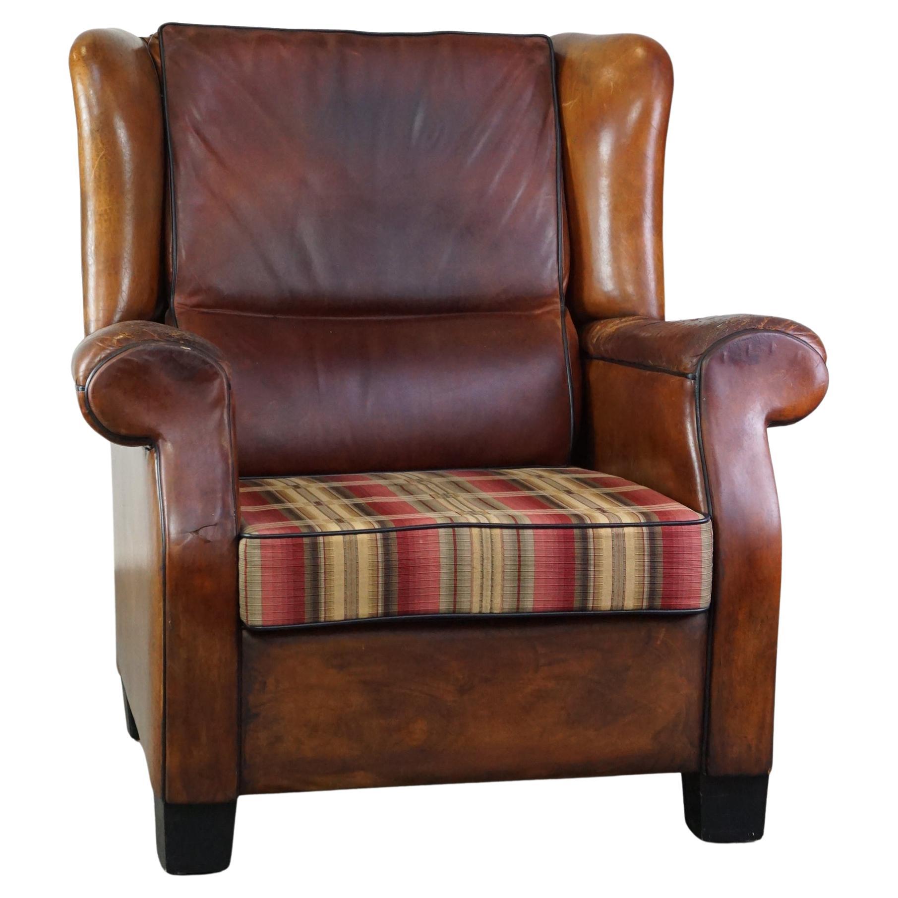 Very large worn sheepskin wing chair with a checked seat cushion For ...
